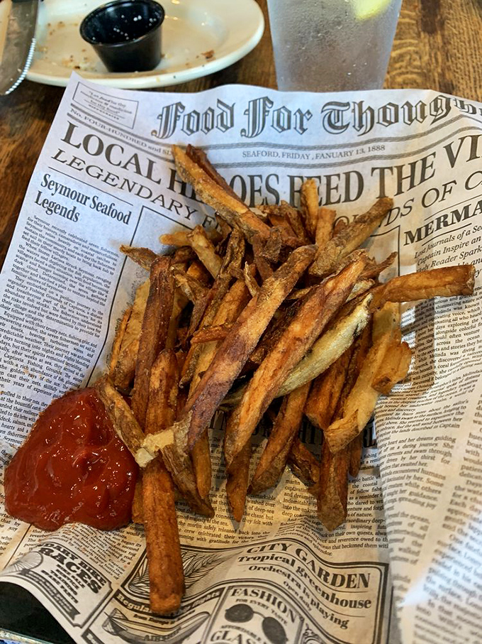 These aren't ordinary fries—they're crispy potato vessels for ketchup, served on vintage newspaper because tradition tastes better than pretension.