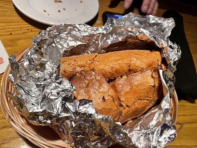 Garlic bread that arrives wrapped like a present. Unwrap it and the aromatic steam performs a little dance that makes your mouth immediately water.