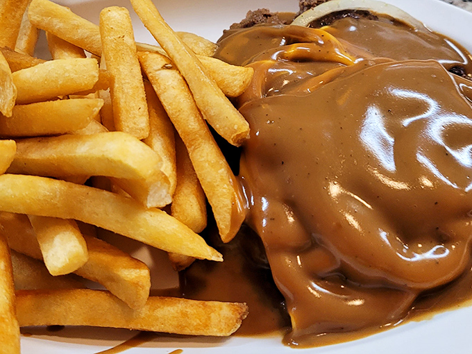 Hamburger steak swimming in rich gravy alongside golden fries&mdash;comfort food that whispers "everything's going to be alright" with every savory bite.