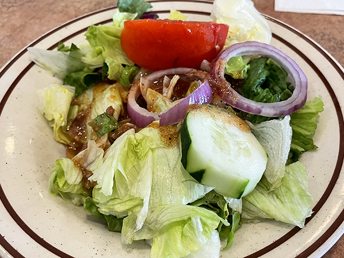 A house salad that doesn't apologize for being simple&mdash;crisp lettuce, ripe tomato, and purple onion rings that mean business.