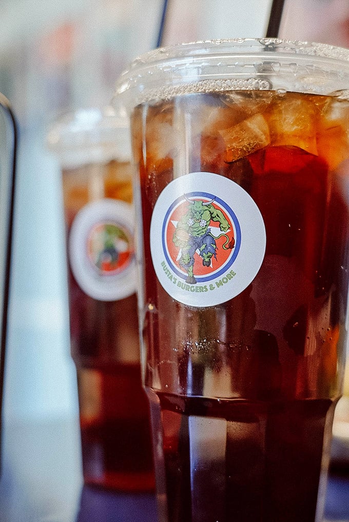 Even the drinks wear superhero logos at Busta's. This tea isn't just refreshing; it's your sidekick for the burger battle ahead.