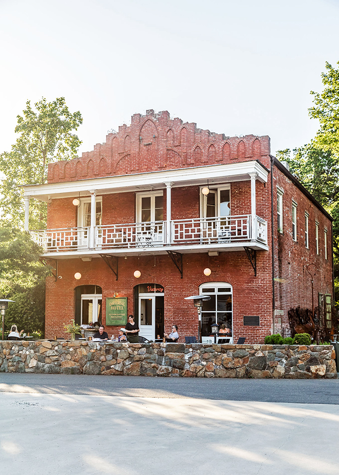 The Imperial Hotel glows at sunset, its brick facade and wrought-iron balcony inviting you to step back in time.
