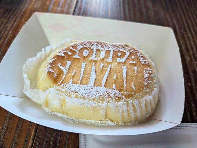 Not just dessert, but edible art! The Japanese cheesecake wears its "Soupa Saiyan" branding like a superhero emblem, dusted with powdered sugar.
