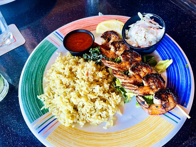 Skewered shrimp nestled against yellow rice like sunbathers on golden sand. That little cup of slaw is the perfect cool-down.