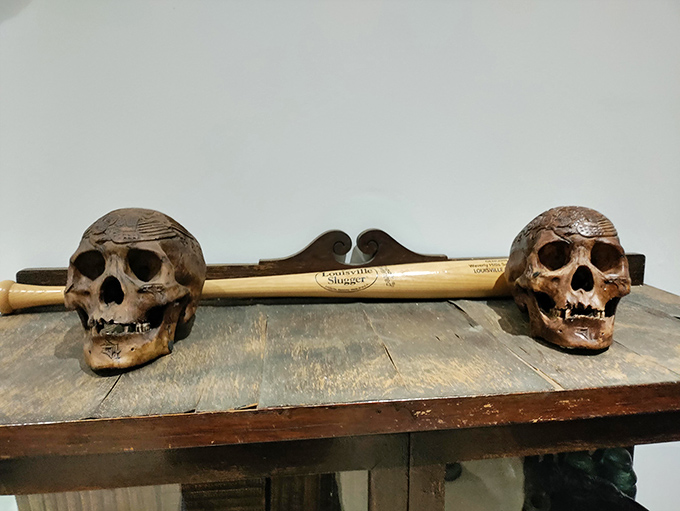 "Slugger meets afterlife." These decorative skulls flanking a Louisville Slugger bat create the kind of home decor that raises eyebrows at dinner parties.