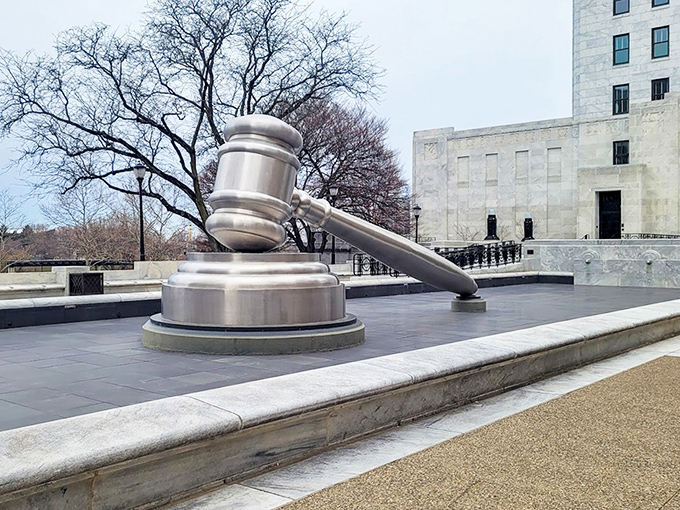 The gavel's handle stretches dramatically across the plaza, making you wonder if Paul Bunyan moonlighted as a Supreme Court Justice in his spare time.