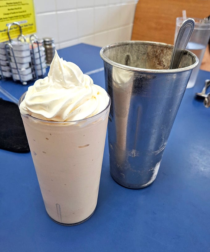 The milkshake arrives with whipped cream mountain and metal mixing cup sidekick. It's thick enough to make your straw stand at attention.