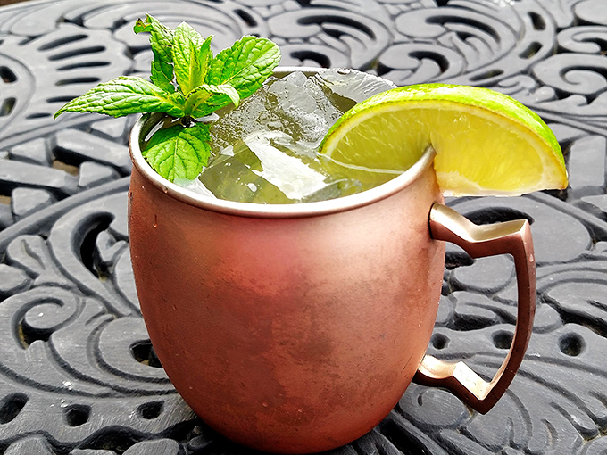 A copper mug Moscow Mule glistens with condensation, its mint sprig standing tall like a tiny flag claiming victory in the battle against ordinary drinks.