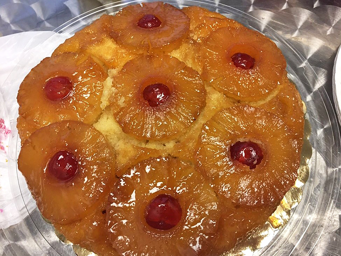 The pineapple upside-down cake glistens with caramelized sweetness, each cherry standing guard over its pineapple kingdom like tiny ruby sentinels.