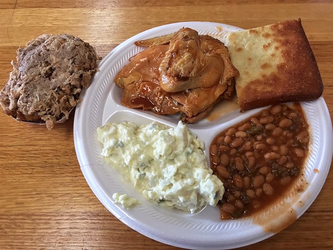 The full experience on one plate: chopped pork, potato salad, baked beans, and that glorious cornbread. This isn't just lunch—it's a cultural education.