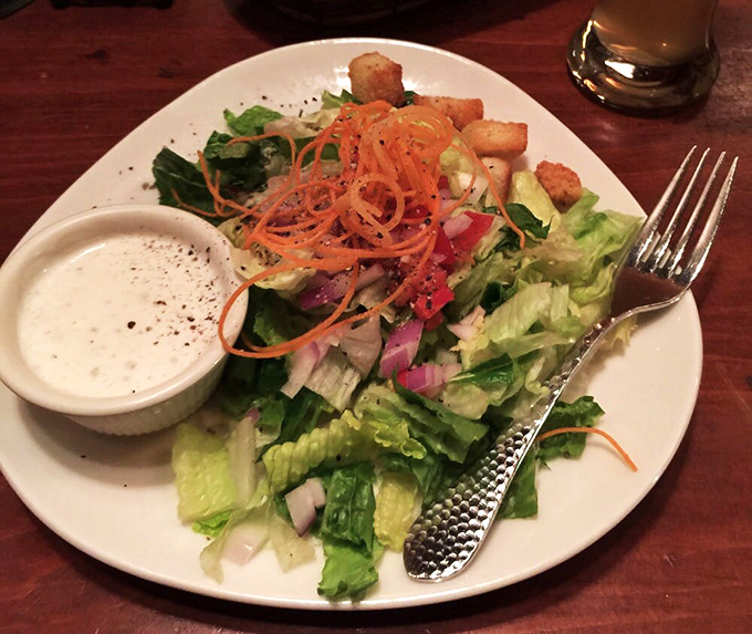 A house salad that defies the "obligatory vegetable" category, with crisp greens, vibrant carrots, and croutons that actually deserve their place.