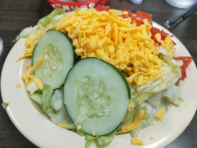 A simple salad stands ready for duty&mdash;the designated healthy option that somehow still feels indulgent when everything around it is comfort food royalty.