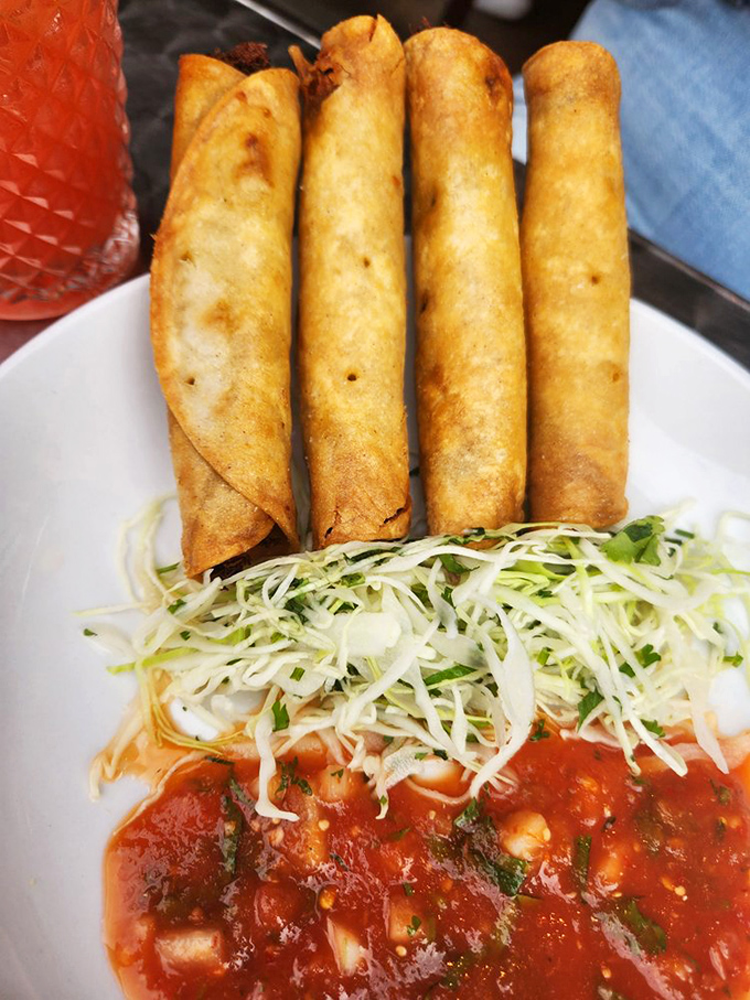 Taquitos standing at attention like delicious sentinels, ready to defend your right to dip them in that vibrant red sauce.