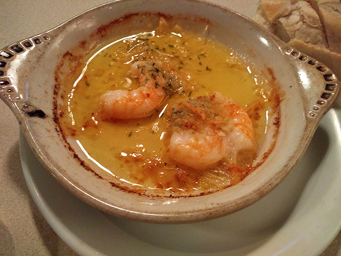 Two perfect Gulf shrimp swimming in butter and herbs—proof that sometimes the simplest preparations yield the most profound flavors.