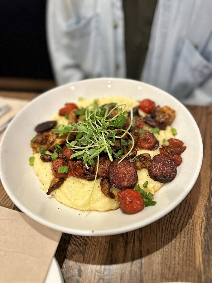 Creamy grits cradle savory toppings like a culinary lullaby. The dish whispers of Southern comfort while showcasing Alaska's talent for cross-country culinary translation.