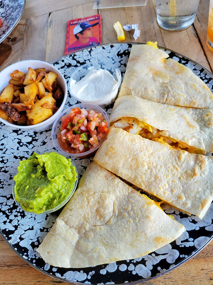 Breakfast quesadilla that's ready for its close-up, surrounded by a supporting cast of potatoes, salsa, and guacamole that deserve their own spotlight.