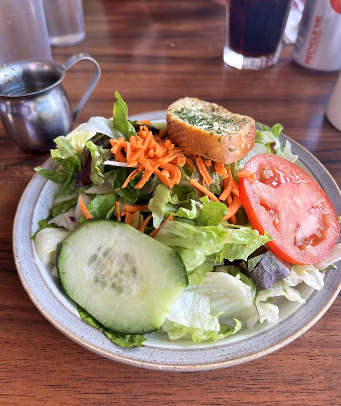 A side salad that actually tries&mdash;crisp greens, vibrant veggies, and that slice of tomato looking like it just came from someone's garden.