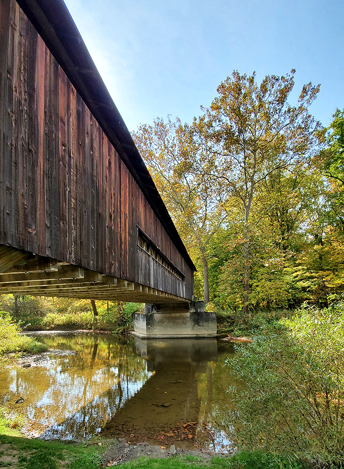 The side view reveals how the bridge hugs the riverbank. Those weathered planks tell stories of horse-drawn carriages and Model Ts.