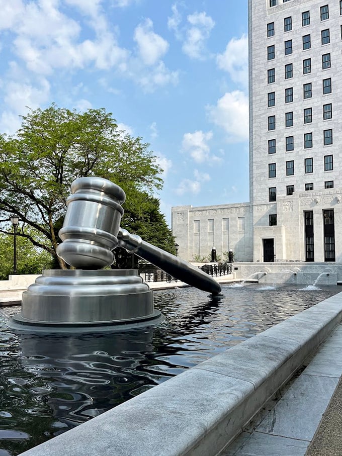 Justice takes a dip! The World's Largest Gavel gleams in summer sunshine, its metallic surface reflecting in the surrounding pool like a legal Narcissus admiring itself.