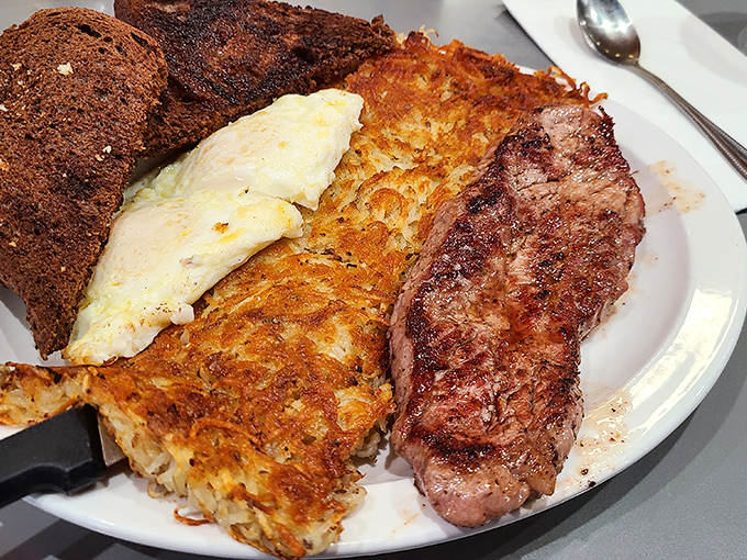 The breakfast trinity: perfectly cooked eggs, hash browns with the ideal crisp-to-tender ratio, and steak that makes morning feel like a celebration.