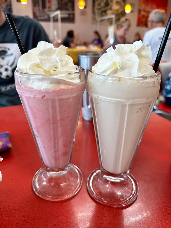 Milkshakes so thick they defy gravity, topped with whipped cream mountains. One strawberry, one vanilla, both worth the brain freeze.