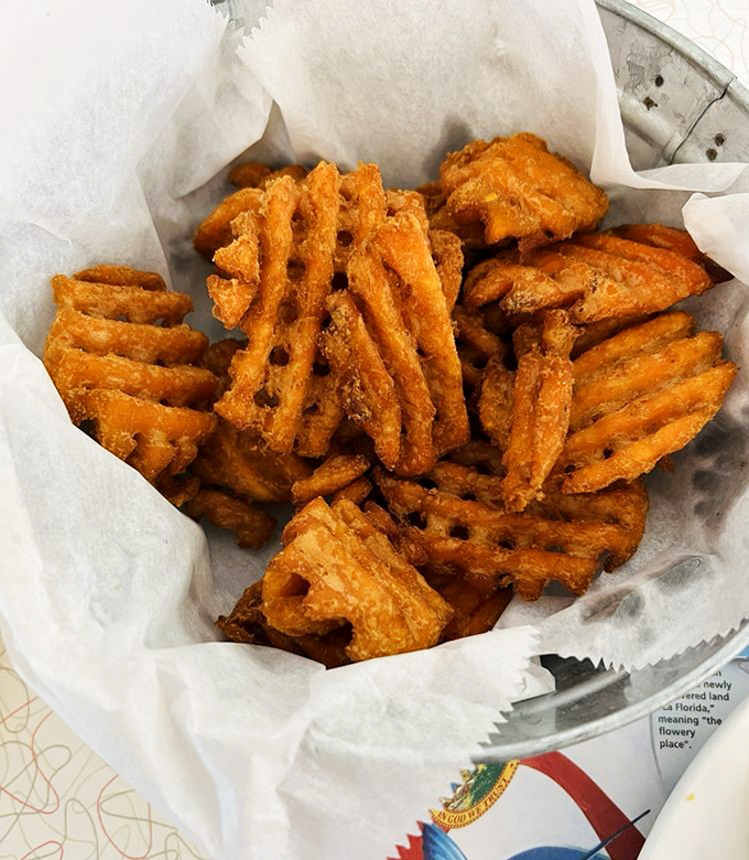 These aren't just sweet potato waffle fries—they're edible architecture, crispy lattice-work vessels designed specifically for ketchup transportation.