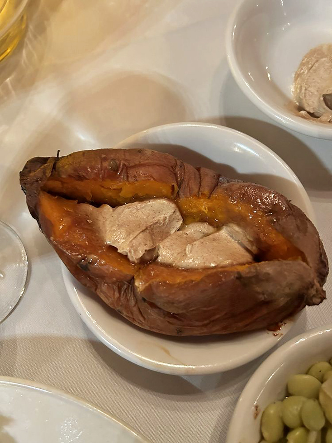 A baked sweet potato that's been split open like a treasure chest, revealing its orange flesh adorned with melting cinnamon butter &ndash; comfort food that whispers "you made the right choice."