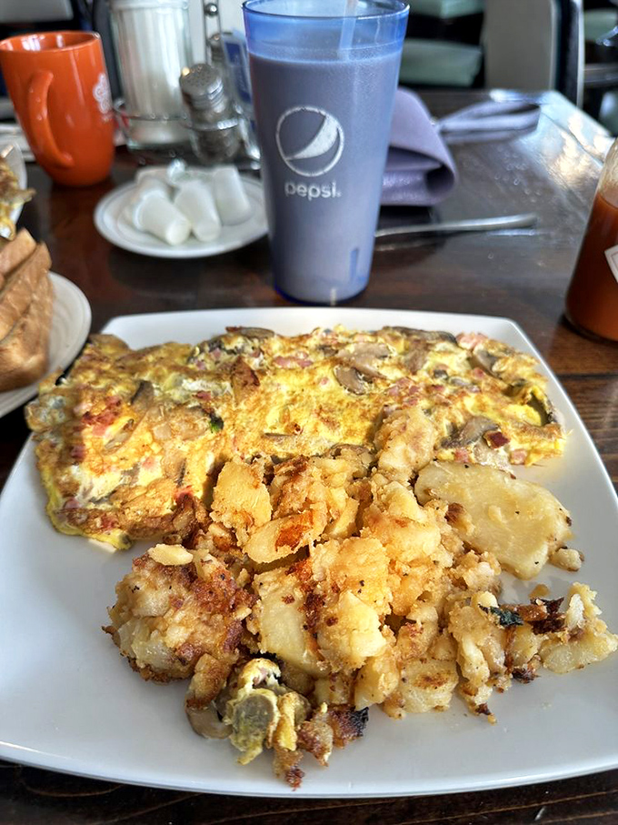 This omelet doesn't just contain mushrooms; it embraces them in a fluffy egg blanket alongside home fries that look hand-cut by someone who cares.