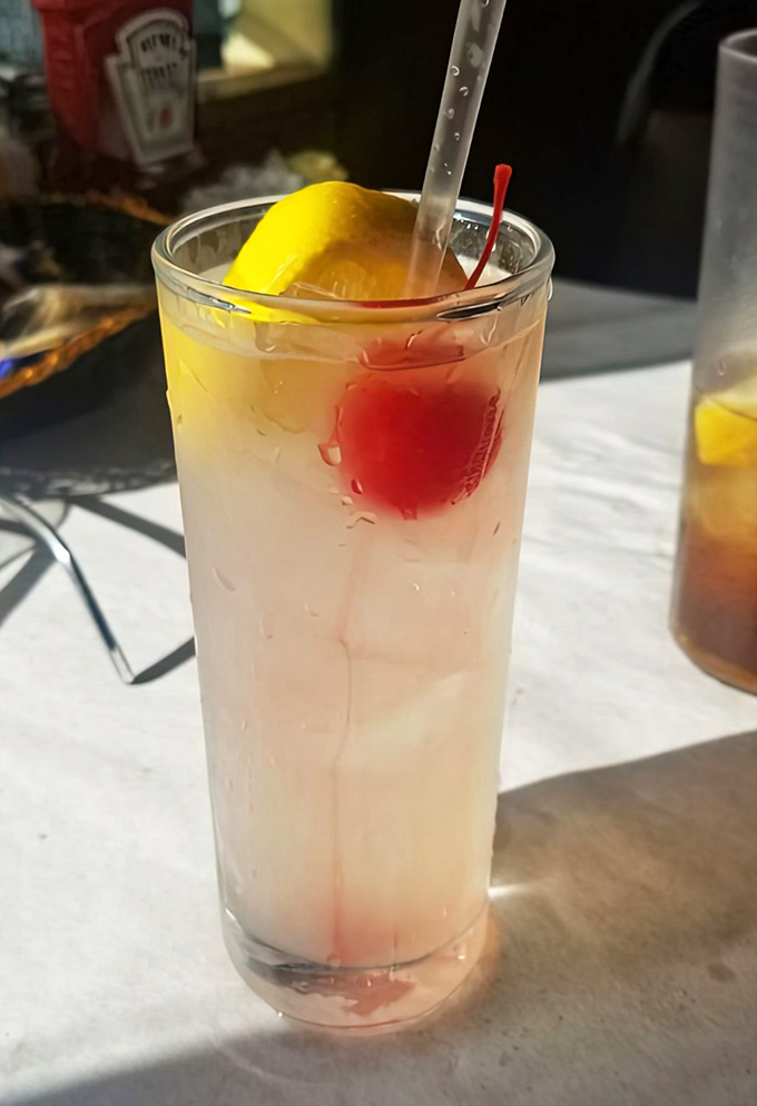 A Tom Collins with that signature cherry and lemon slice—because nothing complements seafood quite like a refreshing, classic cocktail with just the right amount of zing.