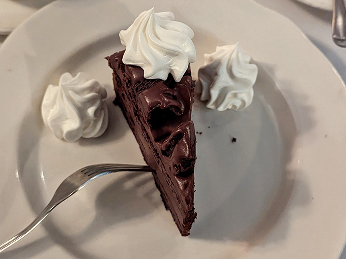 Triple chocolate cake that doesn't need a fancy French name to impress. Those dollops of whipped cream aren't garnish—they're necessary supporting actors in this dessert drama.