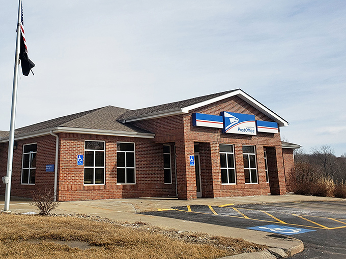 The post office stands ready for duty, a brick sentinel ensuring birthday cards and bills alike reach their destinations in this charming river town.