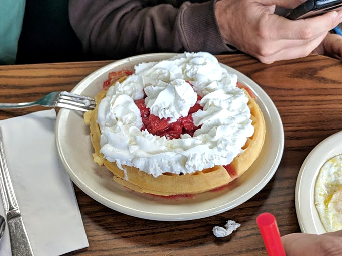 A waffle that's both canvas and masterpiece, topped with strawberries and whipped cream—breakfast masquerading as celebration.