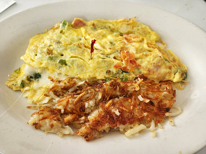 This Western omelet with crispy hash browns isn't just a meal &ndash; it's edible sunshine folded around peppers, onions, and ham with a side of potato perfection.