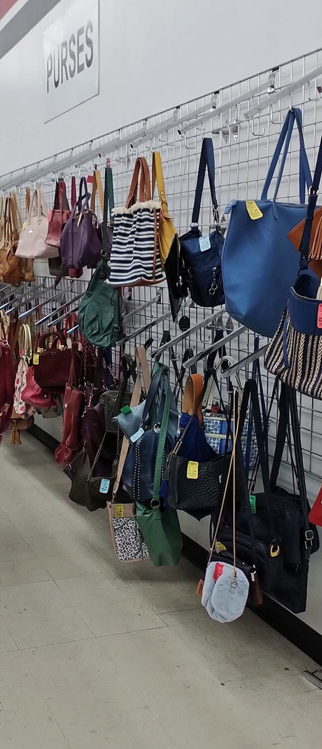 The handbag wall&mdash;where designer dreams and practical carryalls hang side by side, waiting to accessorize your life at thrift store prices.