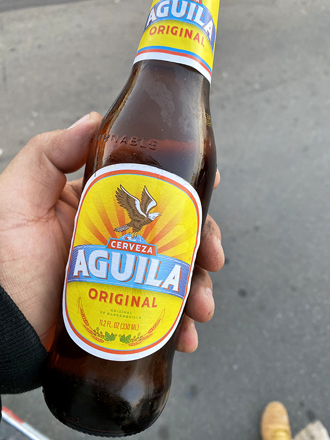 An ice-cold Aguila beer stands ready for duty&mdash;the perfect companion when facing down a burrito that could feed a small village.