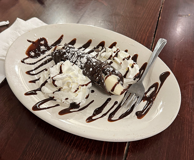 The cannoli&mdash;that magical tube where crispy pastry meets creamy filling&mdash;sits drizzled with chocolate like it's dressed for the dessert equivalent of the Met Gala.