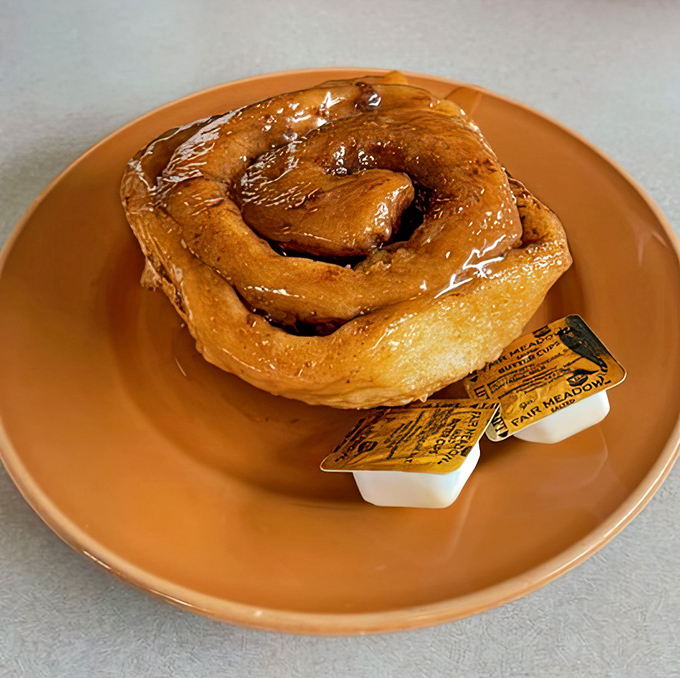 That caramel roll could double as a sculpture—sticky, sweet, and large enough to require strategic planning for consumption.