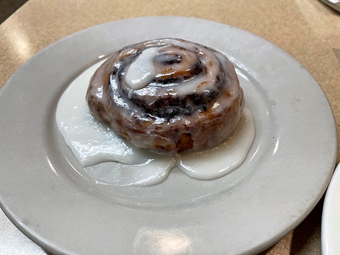 This cinnamon roll isn't just dessert; it's a warm, gooey hug on a plate, swimming in icing that's not afraid to make a statement.