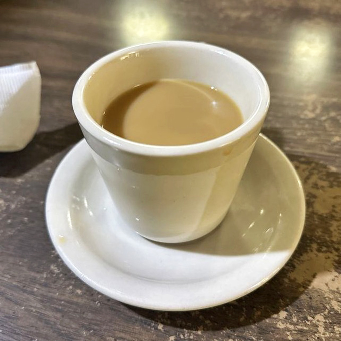 The coffee comes in these sturdy white mugs that feel like they've survived decades of morning conversations and newspaper-reading sessions.