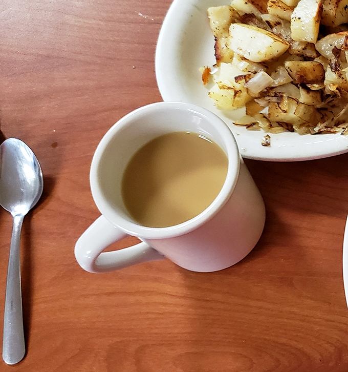 The humble coffee cup, faithful companion to every breakfast adventure, standing by while home fries play a delicious supporting role.