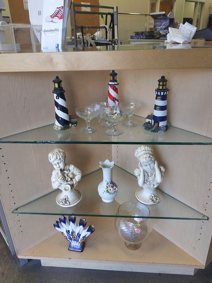 Lighthouse sentinels and porcelain figurines stand at attention on glass shelves&mdash;coastal charm meets southwestern thrift store magic.