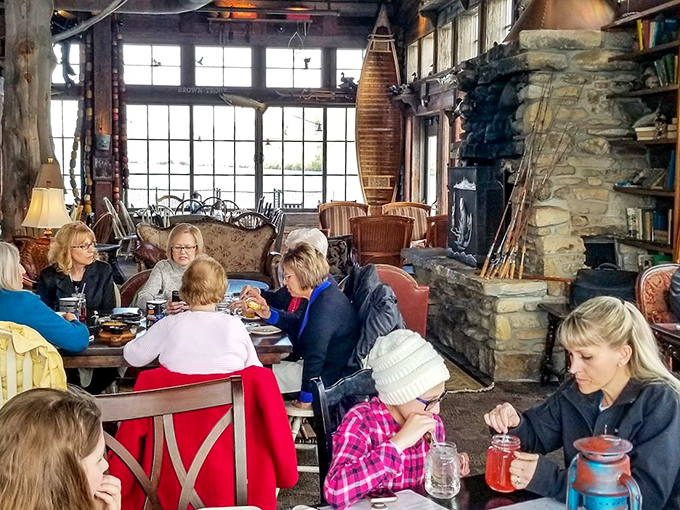 The dining room feels like your outdoorsy uncle's dream living room &ndash; stone fireplace, vintage canoes, and windows framing nature's own watercolor.