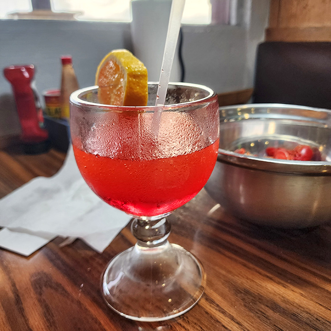 Ruby-red cocktail catching the light &ndash; because sometimes fishing stories need a little liquid encouragement.