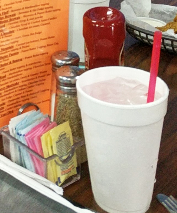 Table essentials: sweetener options in their natural habitat, next to what's surely a milkshake thick enough to require Olympic-level straw strength.