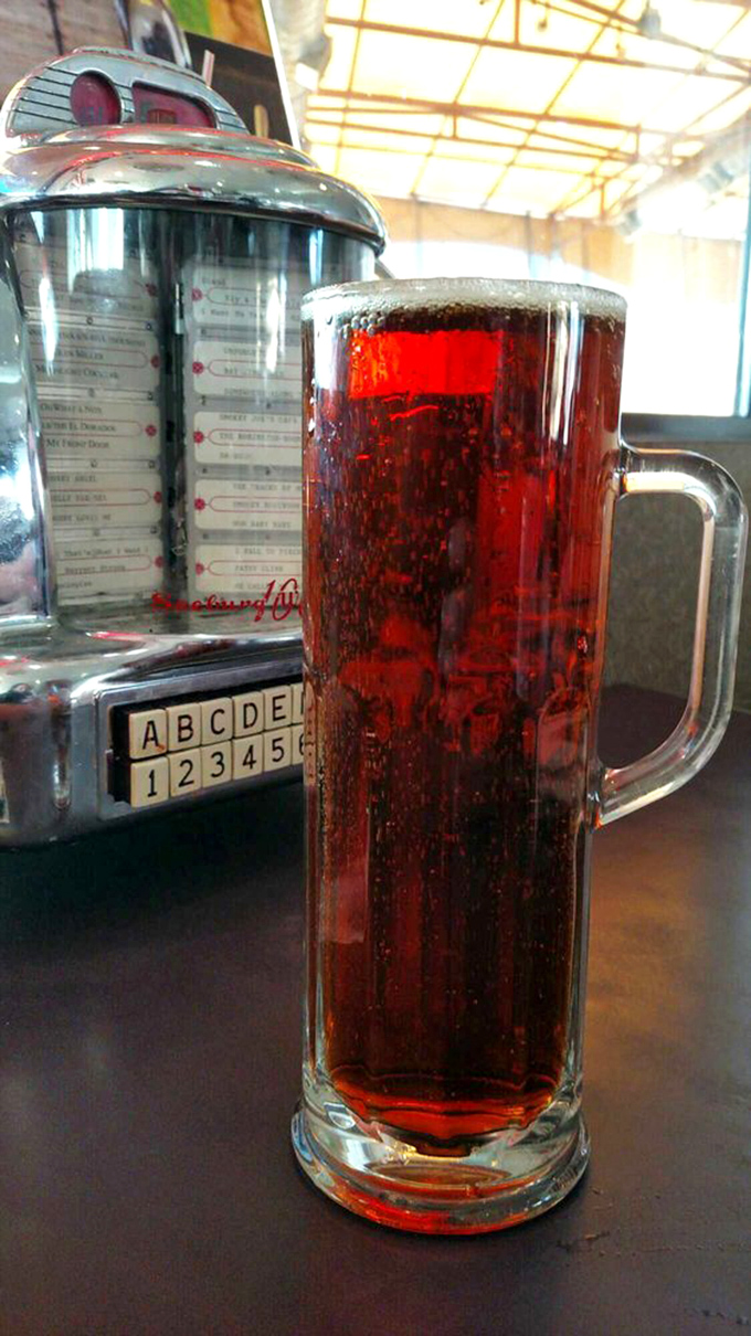 That tall, frosty glass of soda beside a vintage jukebox selector &ndash; pure Americana in liquid form.