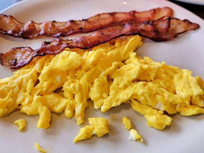 Scrambled eggs so fluffy they might float away if not anchored by those perfectly crisp bacon strips. Breakfast fundamentals executed flawlessly.