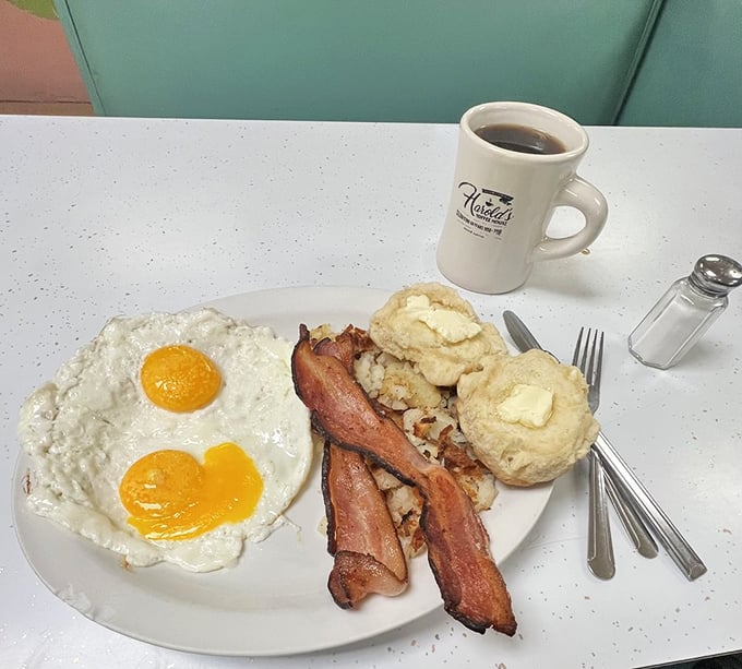 Two sunny-side-up eggs with perfectly crisp bacon and homemade biscuits&mdash;proof that simplicity, when done right, is the ultimate sophistication.
