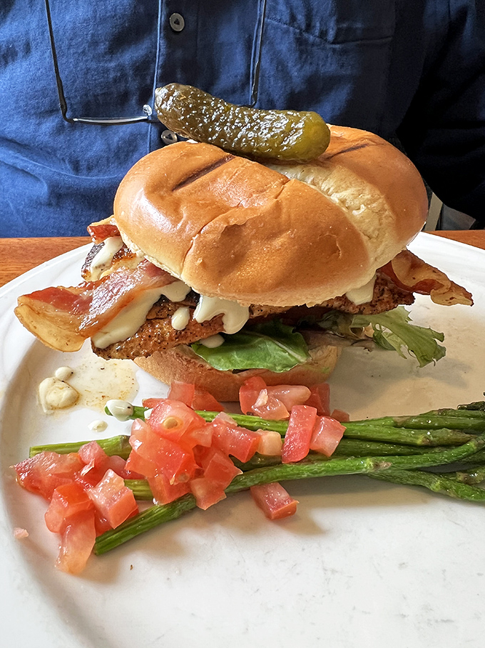 A sandwich that requires both hands and a strategy—crispy fish, melty cheese, and that pickle on top standing guard like it owns the place.