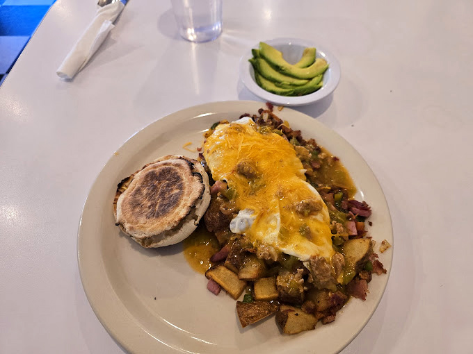 Breakfast nirvana achieved! A mountain of seasoned potatoes crowned with melted cheese and green chili, served with a perfect English muffin and sliced avocado.