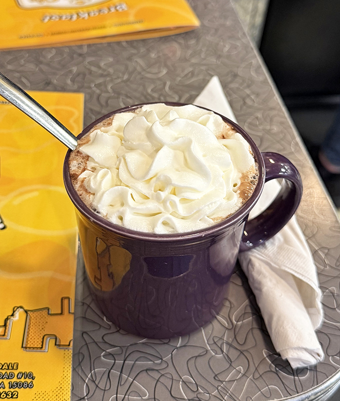 That hot chocolate isn't just a beverage, it's a dessert masquerading as a morning drink, crowned with a cloud of whipped cream.
